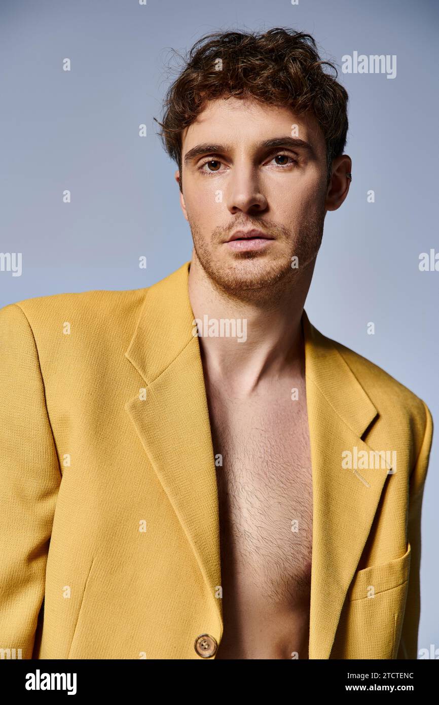 appealing young man in trendy yellow jacket posing attractively on gray ...