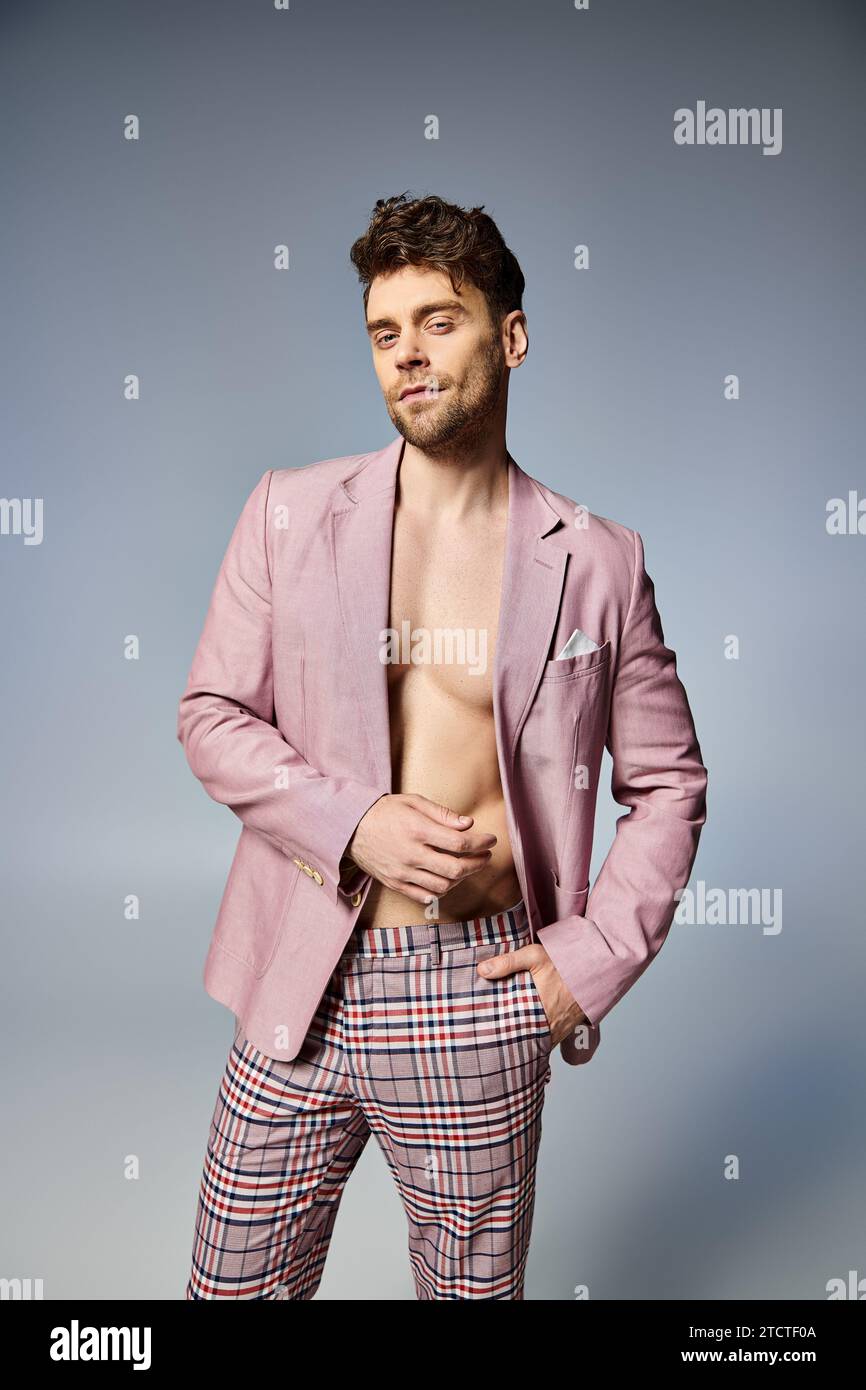 good looking man in unbuttoned vivid pink suit posing alluringly on ...