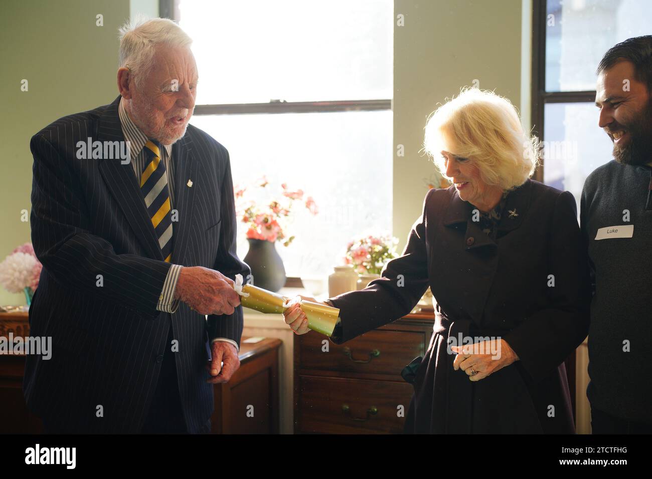 Queen Camilla pulls a Christmas cracker with Sir Terry Waite during a ...