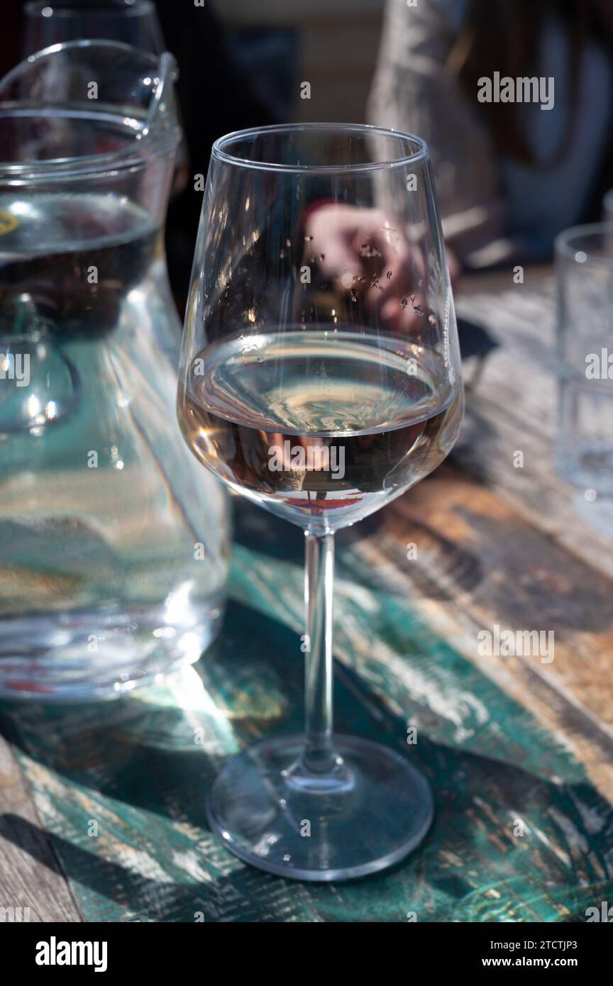 Drinking of pinot grigio dry cold wine, served outdoor in beach cafe in ...