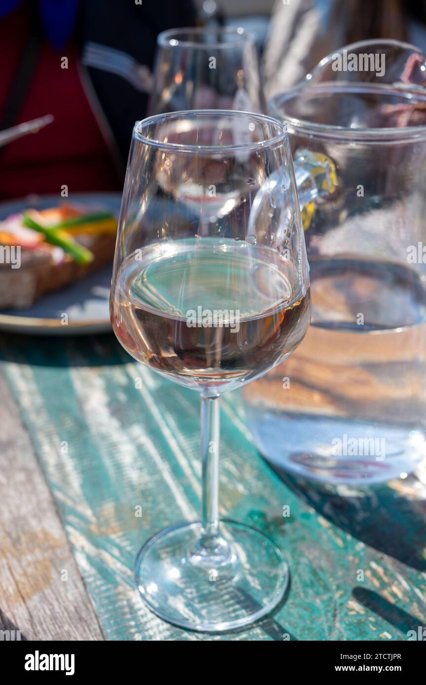 Drinking of pinot grigio dry cold wine, served outdoor in beach cafe in ...