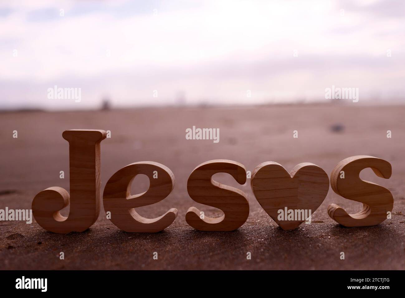 Wooden letters forming the word Jesus on a background of beach sand ...