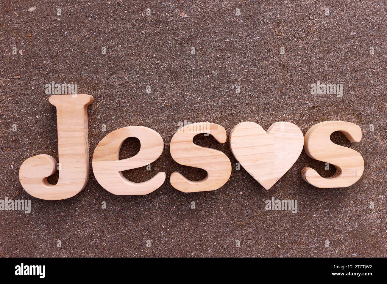 Wooden letters forming the word Jesus on a background of beach sand ...