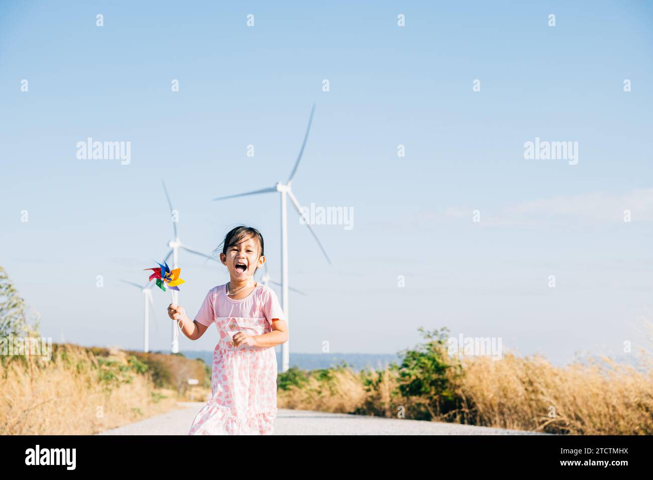 Child's playful exploration by windmills, little girl runs with ...