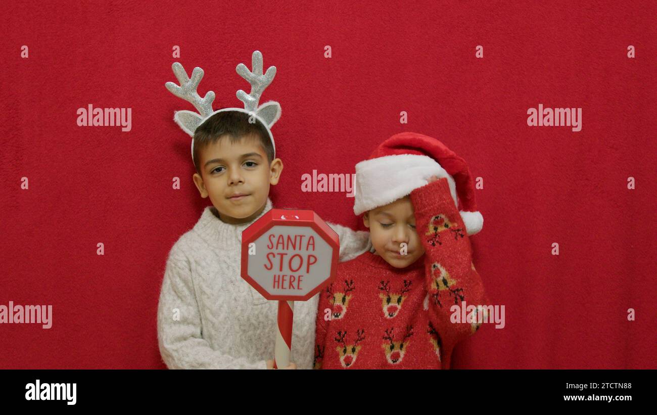Cute kids brothers hugging and showing santa stop here sign. Christmas ...