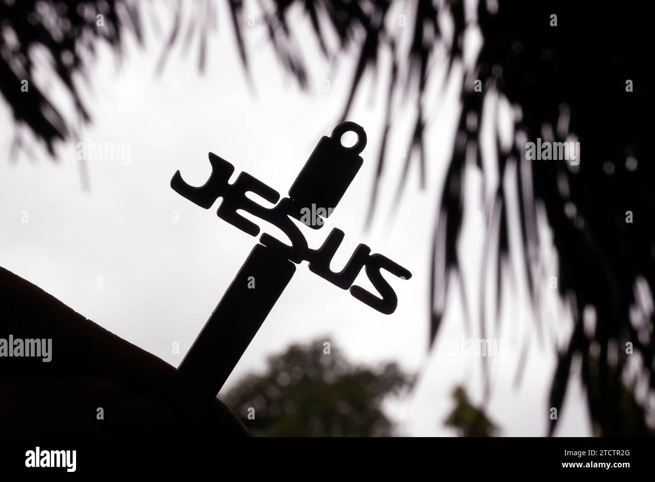 Man holding a christian cross with the name of Jesus against the sky ...