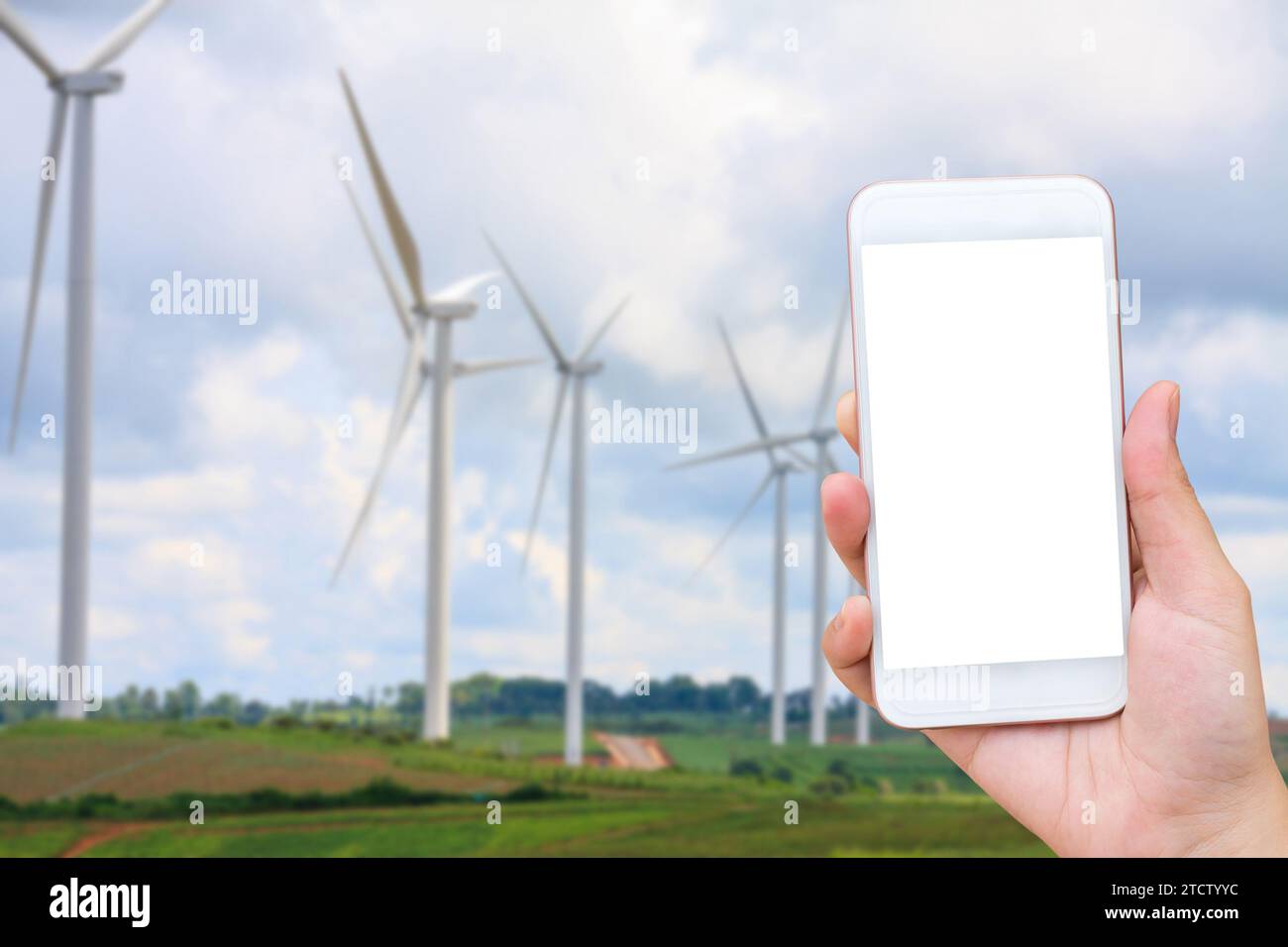 hand holding mobile phone with wind turbines background, renewable ...