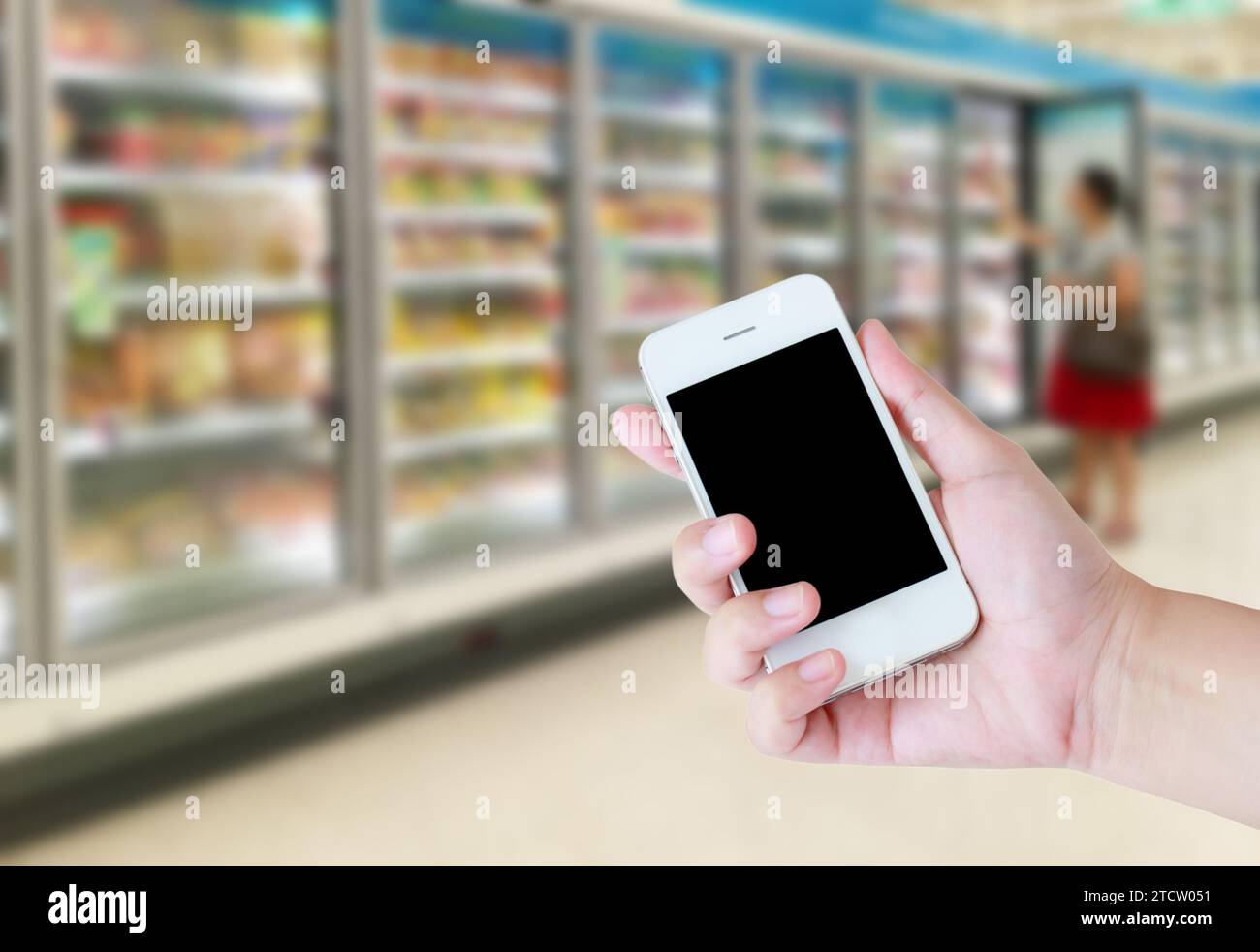 Female hand holding mobile smart phone on Supermarket freezer blur ...