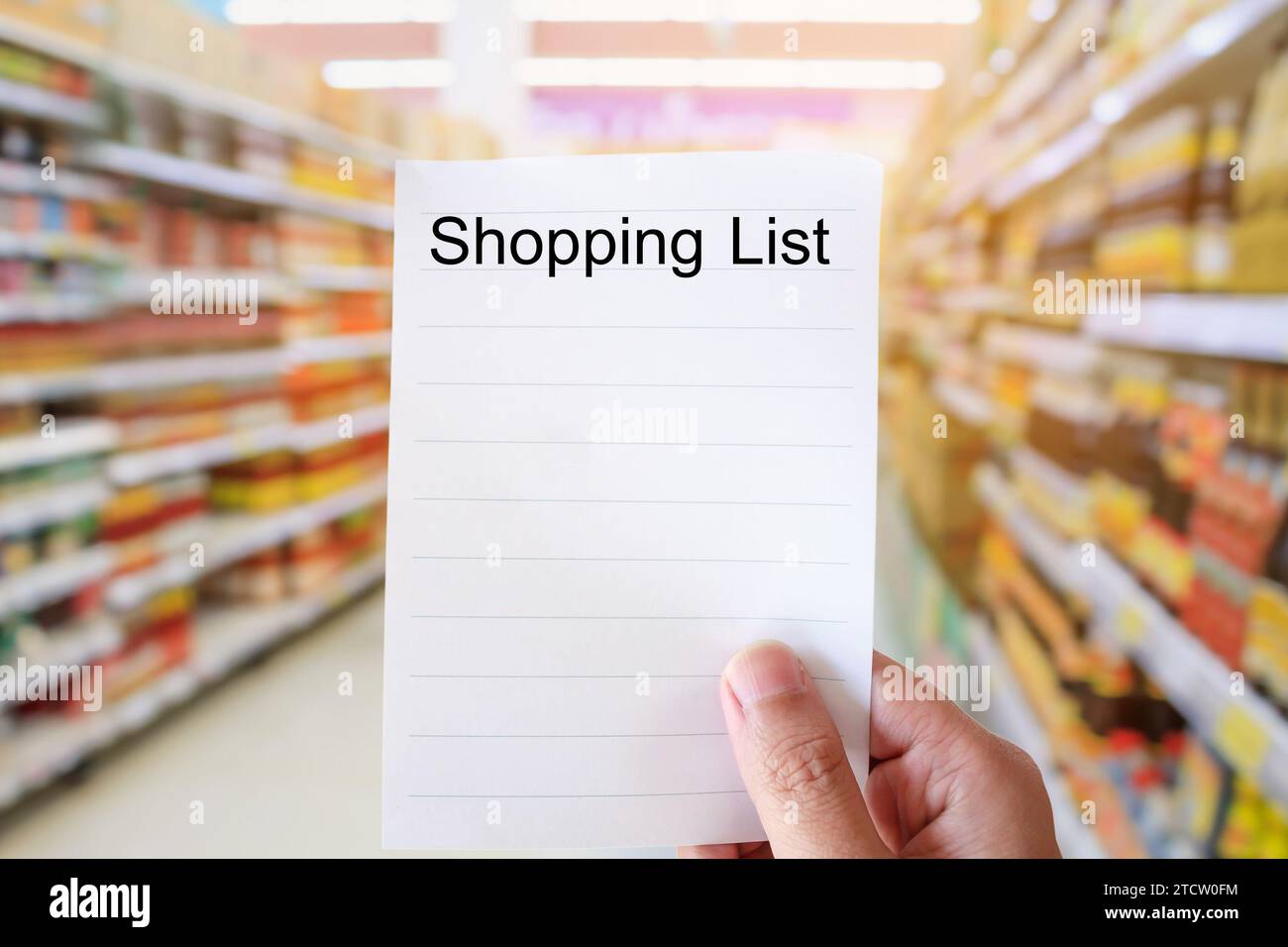 Hand holding shopping list paper over supermarket aisle blur background ...