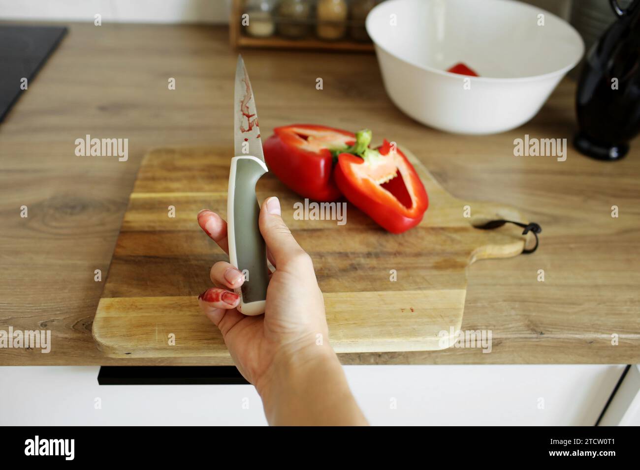 Woman cut her little finger with a knife while cooking vegetable salad ...