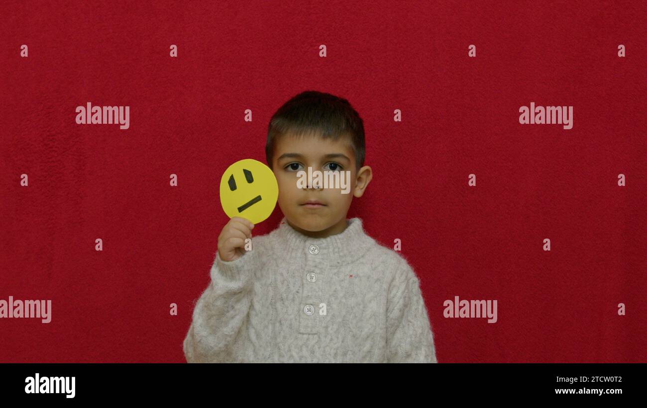 Cute child, a boy unsure of his feelings. Showing yellow emoji. High ...