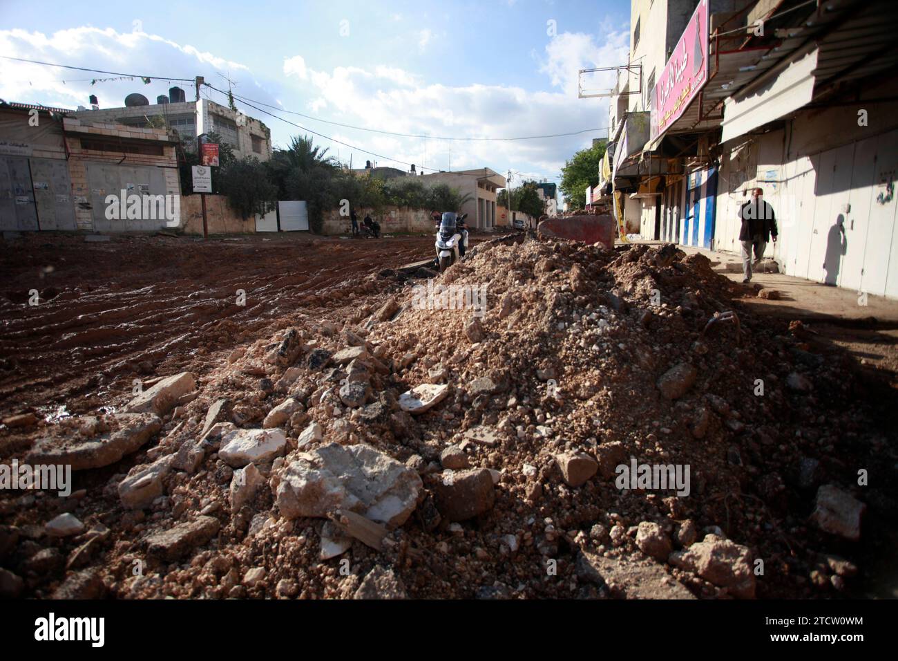 Palestinians walk past a damaged house following an Israeli incursion ...