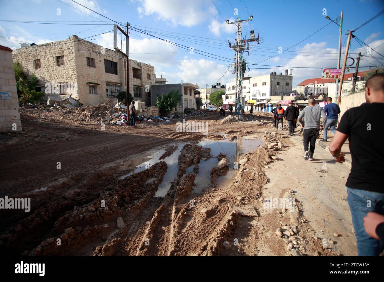 Palestinians walk past a damaged house following an Israeli incursion ...
