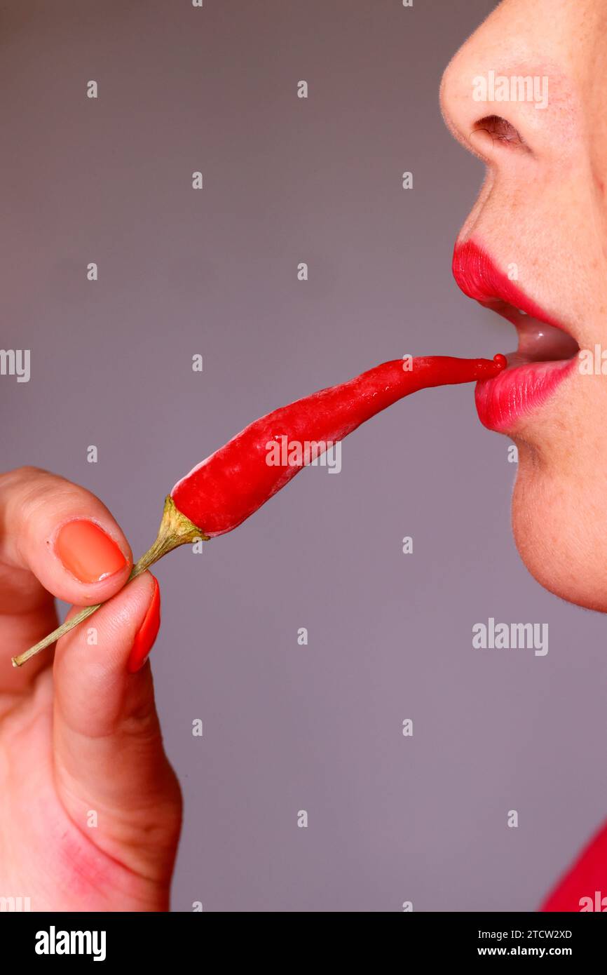 Woman eating spicy red chili. Closeup Stock Photo - Alamy