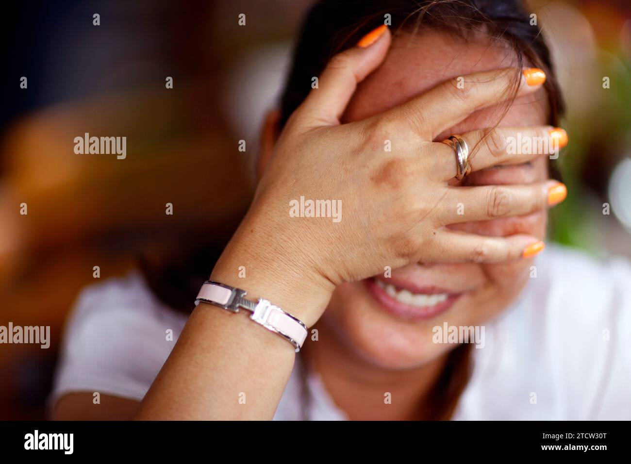 Playful shy woman hiding face with her hand Stock Photo - Alamy