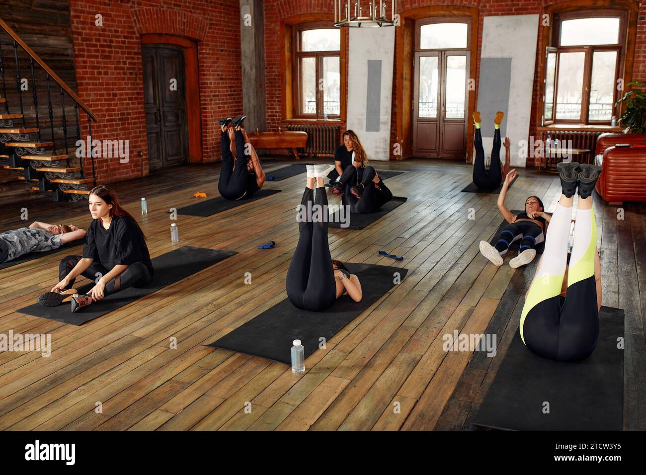 Group of athletic adult men and women performing sit up exercises to ...