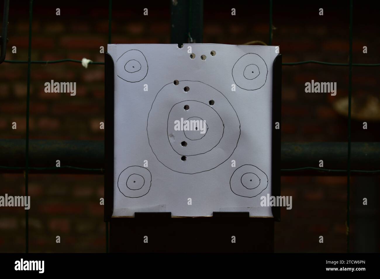 Paper target with several target circles filled with ten bullet holes ...