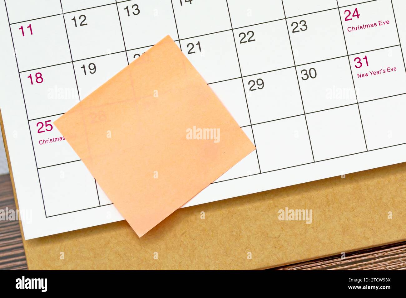 Orange paper sticky note and stuck to a calendar background. Reminder ...