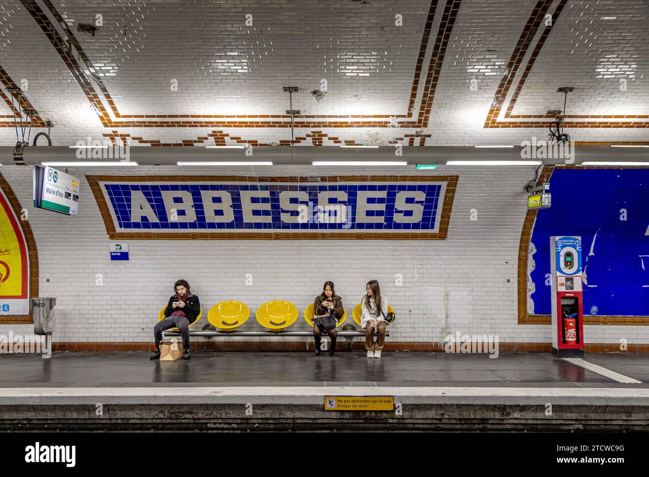 People sitting down waiting for a train at Abbesses metro station in ...