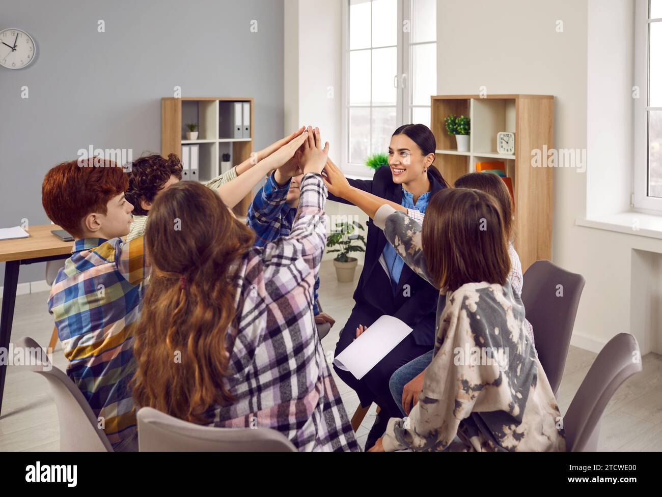 Happy junior school students and teacher giving high five together in ...