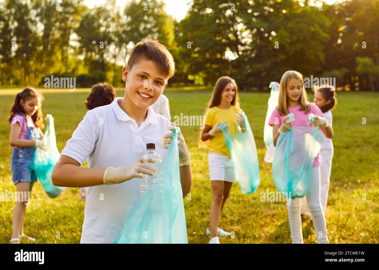 Portrait of preteen boy collecting plastic trash during summer cleanup ...