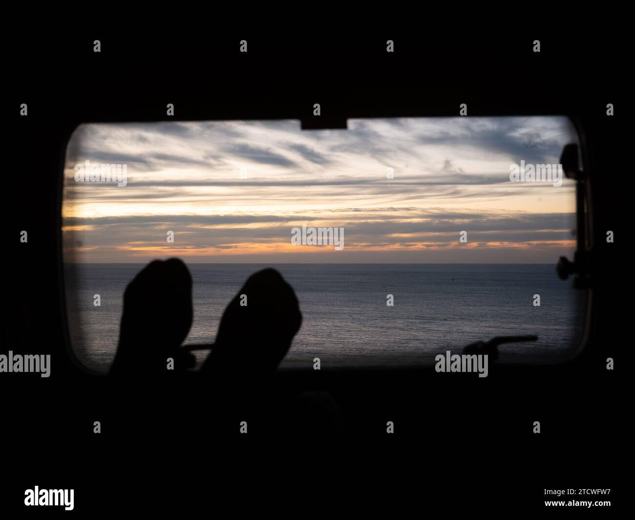 A person is watching the sunrise through the window of the motorhome ...
