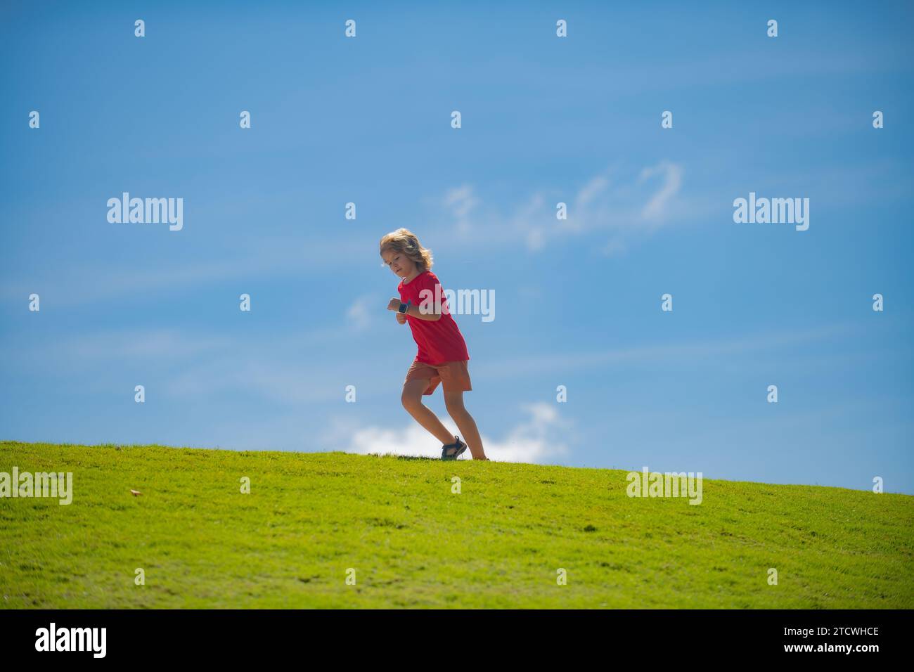 Cute boy running on green grass and blue sky. Run and healthy sport for ...