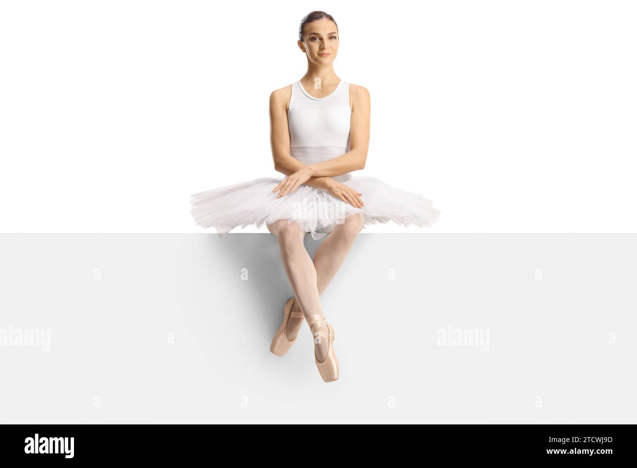 Full length shot of a female ballet dancer in a white dress sitting on ...