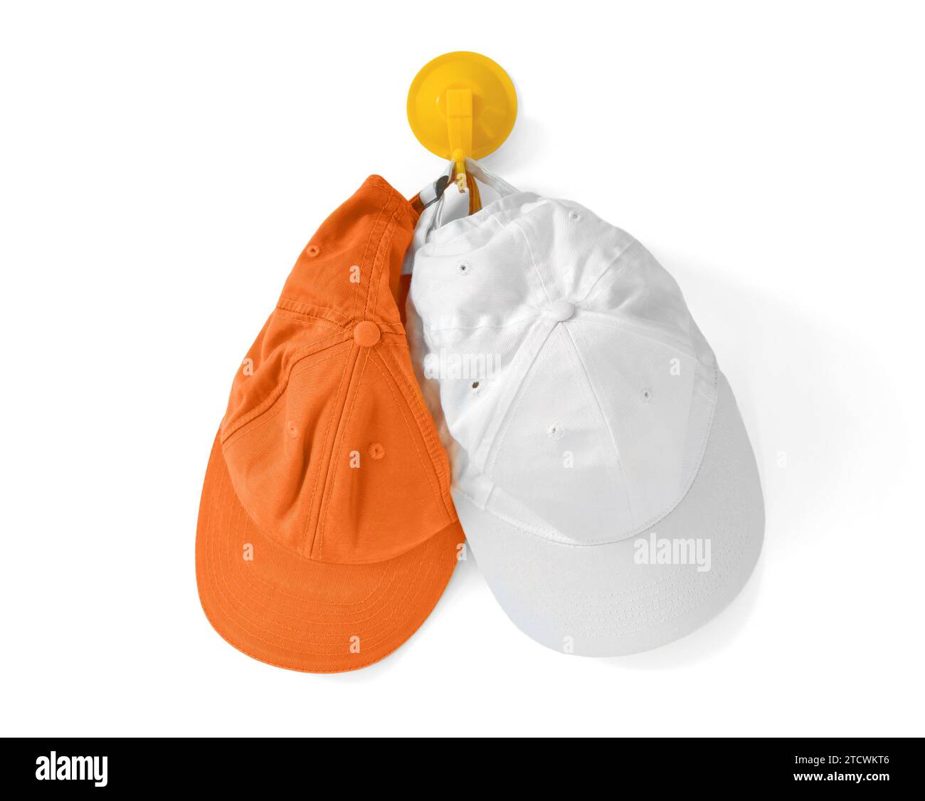 An orange cap and a white one hung on a yellow plastic hook over a ...