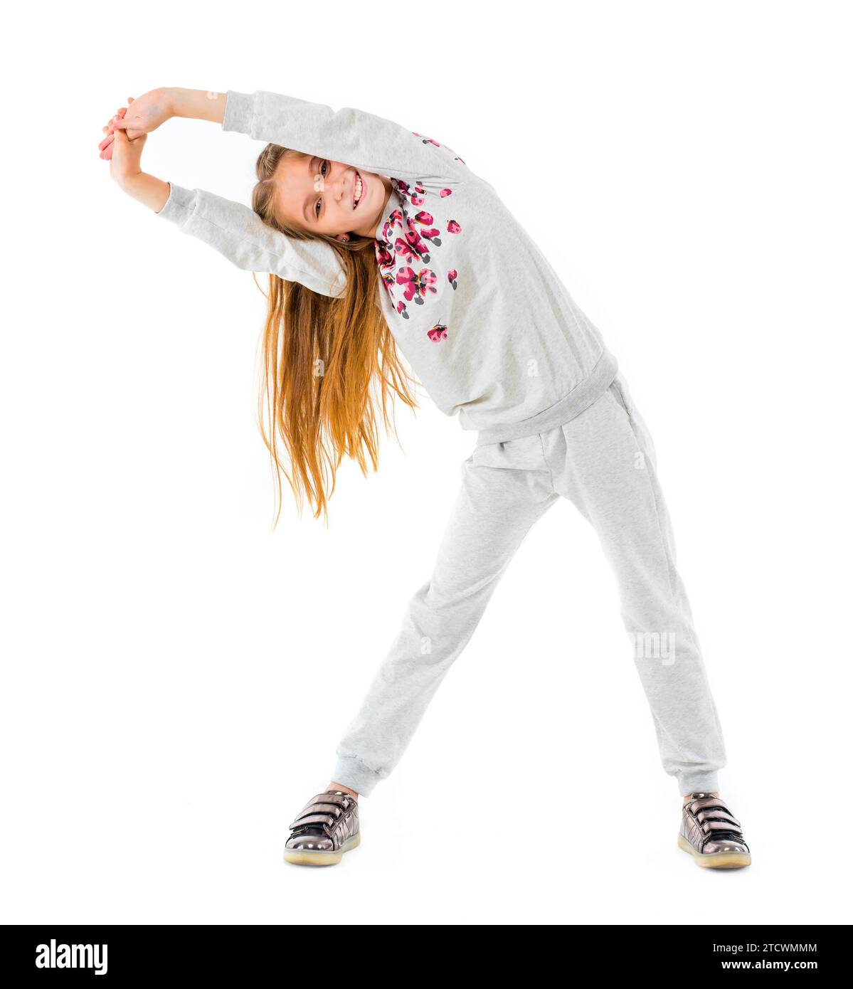 Little positive girl doing yoga side bends isolated on white background ...