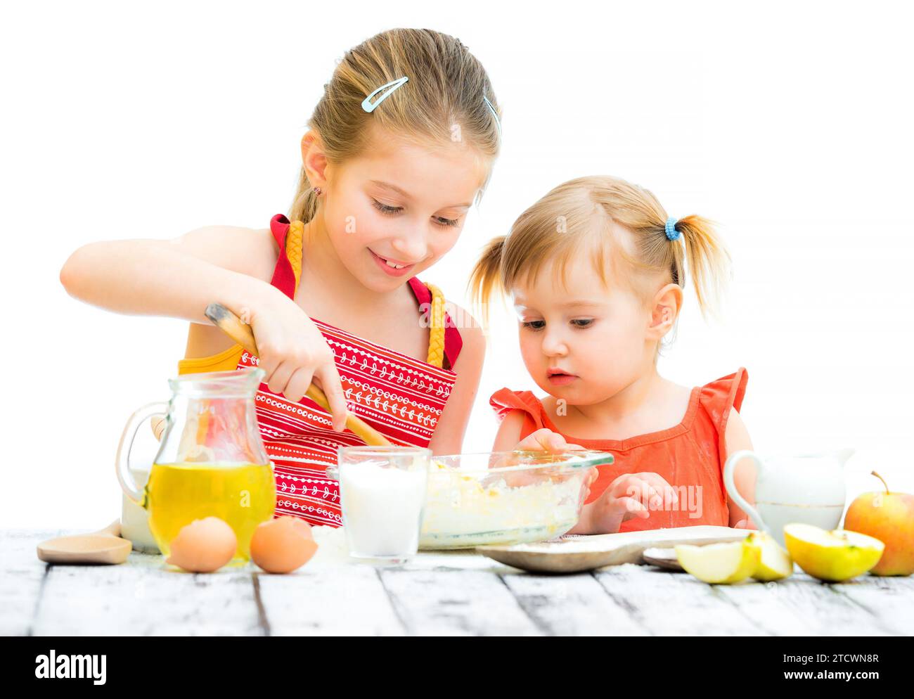 two cute little sisters cooking, on a white background Stock Photo - Alamy