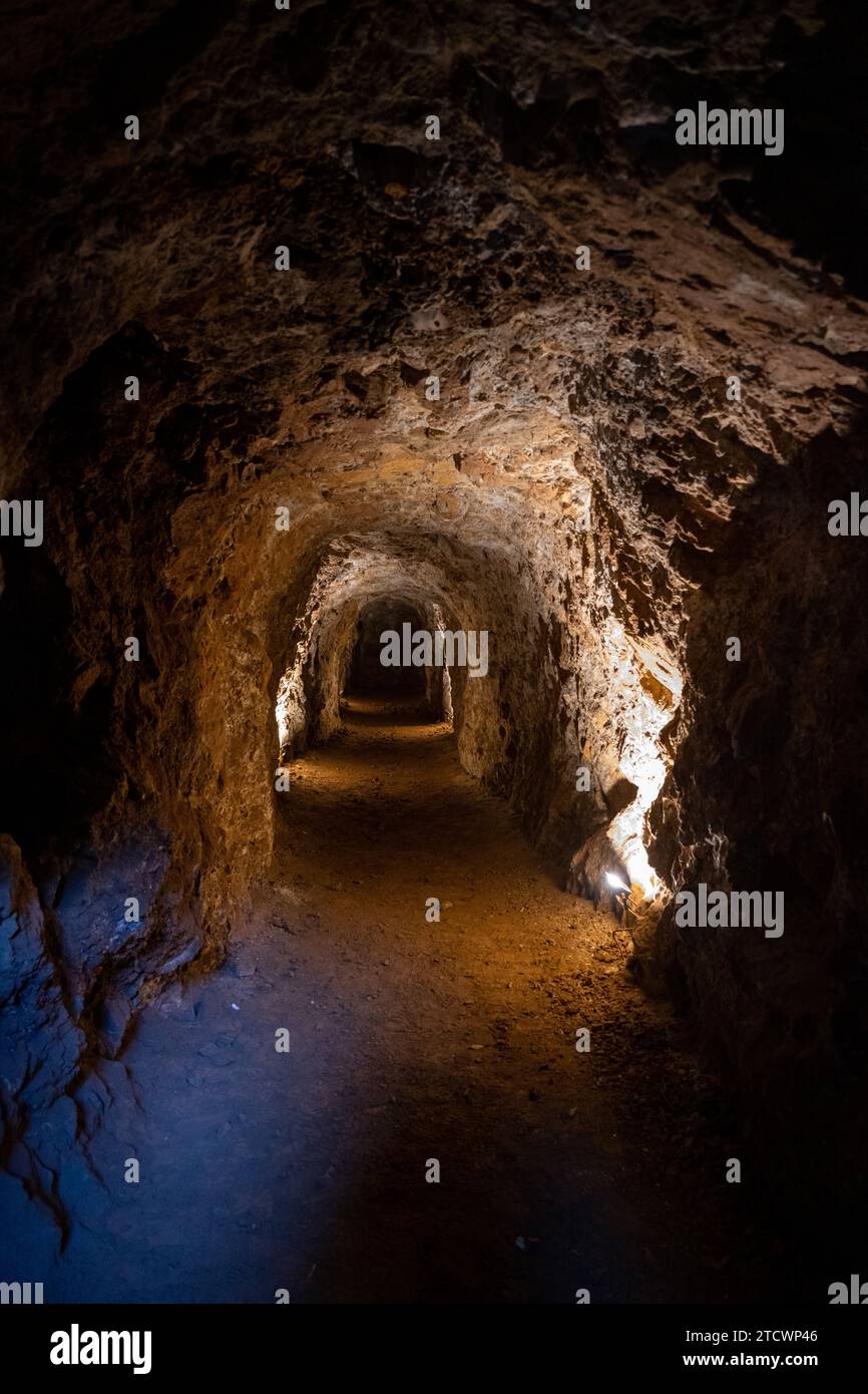 Dimly Lit Ancient Tunnel With Textured Walls Leading Into Darkness Mysterious Underground