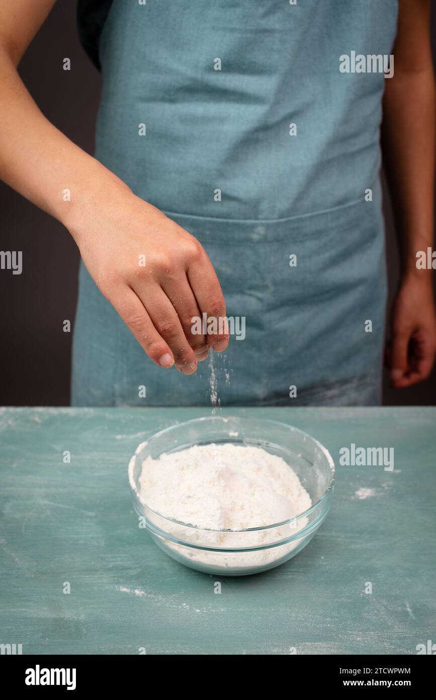 Baker sprinkle salt into the wheat flour, baking ingredient for bread ...