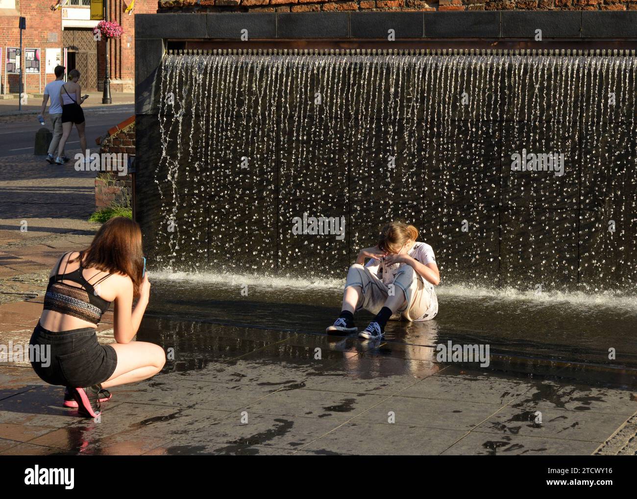Teenage girl having fun getting wet sitting in a fountain by the Amber ...