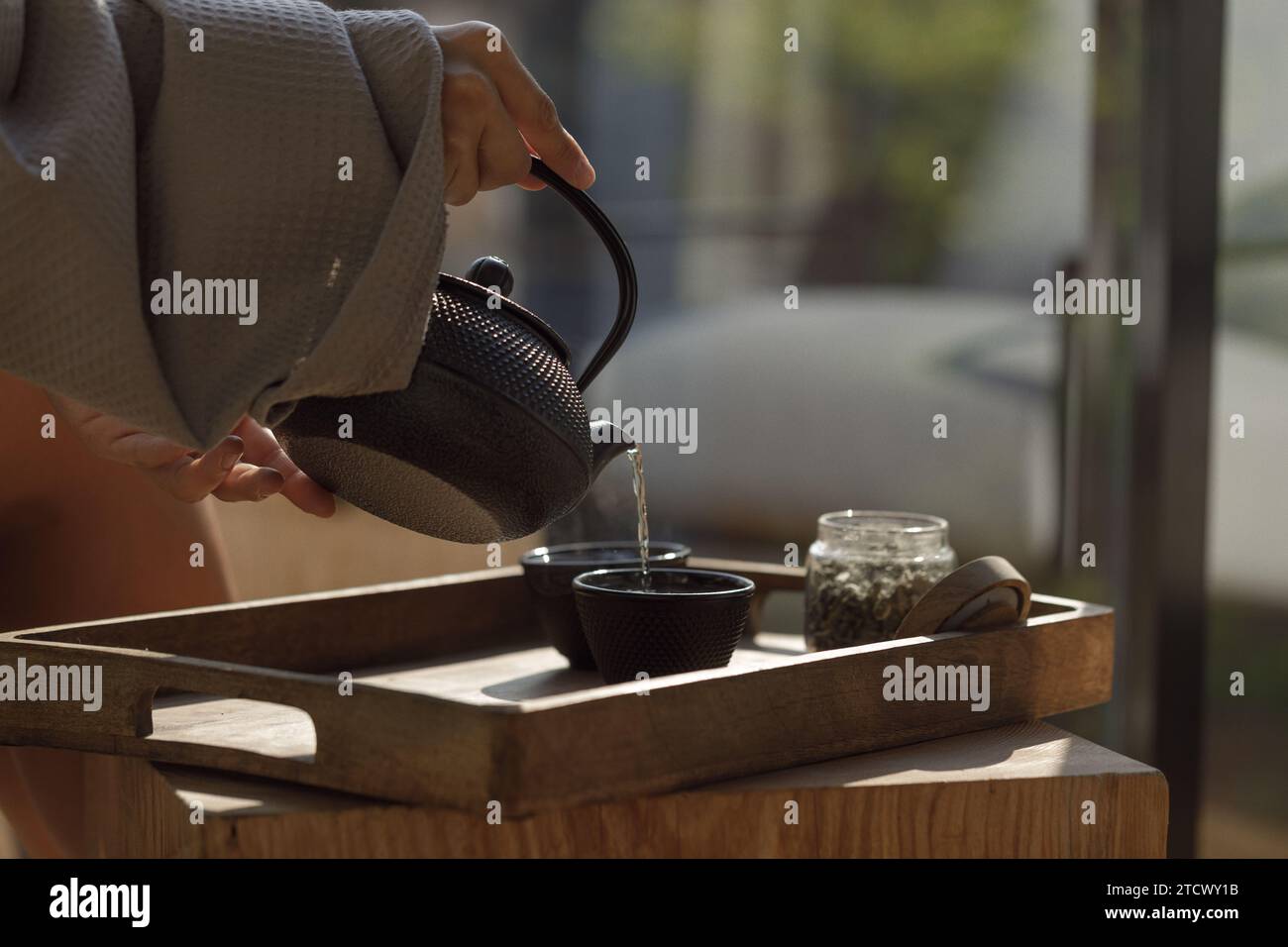 Black cast iron tea pot with herbal tea set up on wood tray ...