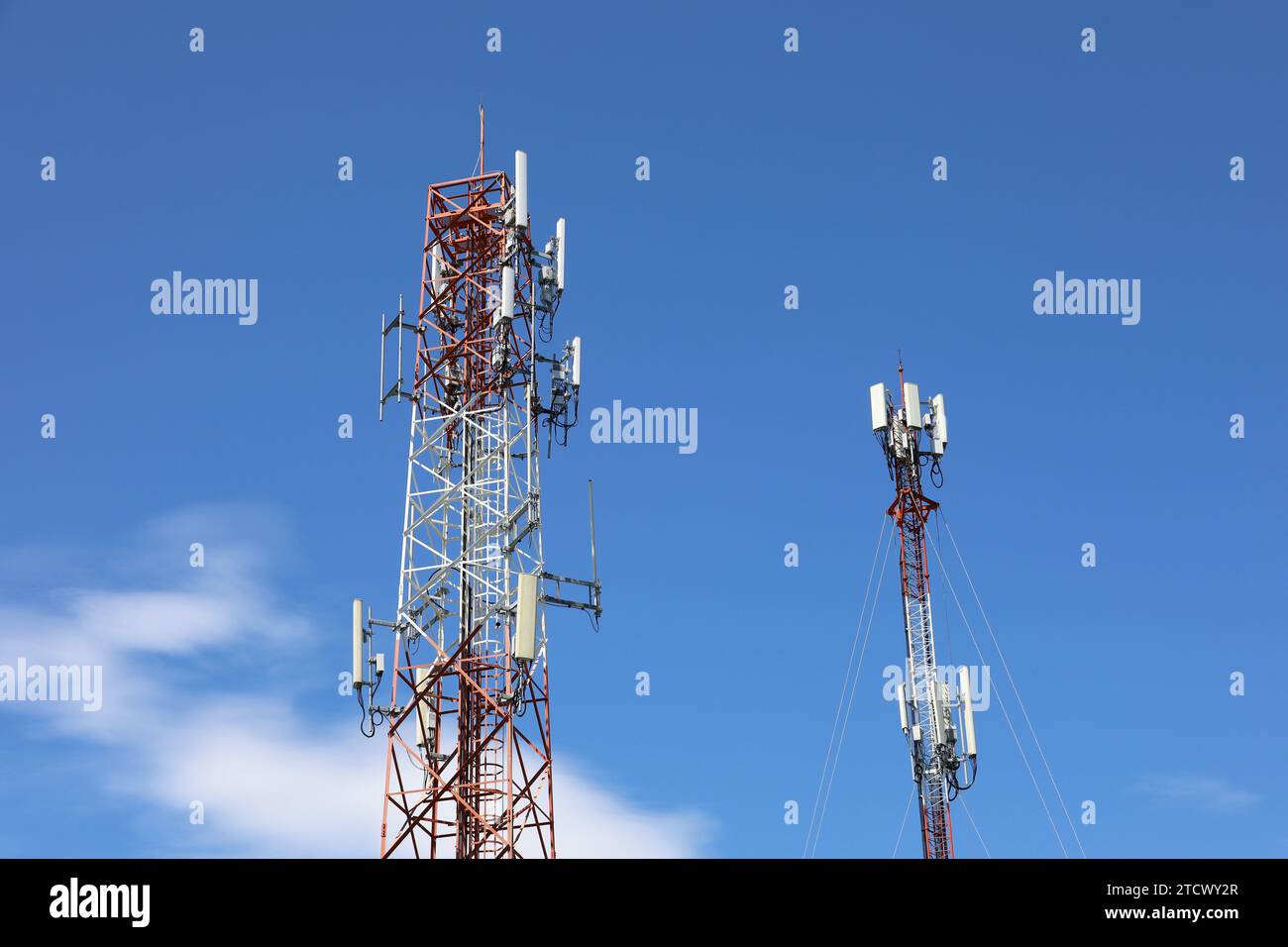 Mobile telecommunication towers on blue sky with white clouds. Cell tower with antennae and ...