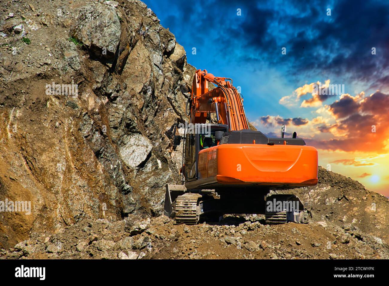 Excavator at a construction site on the side of a hill against a cloudy ...
