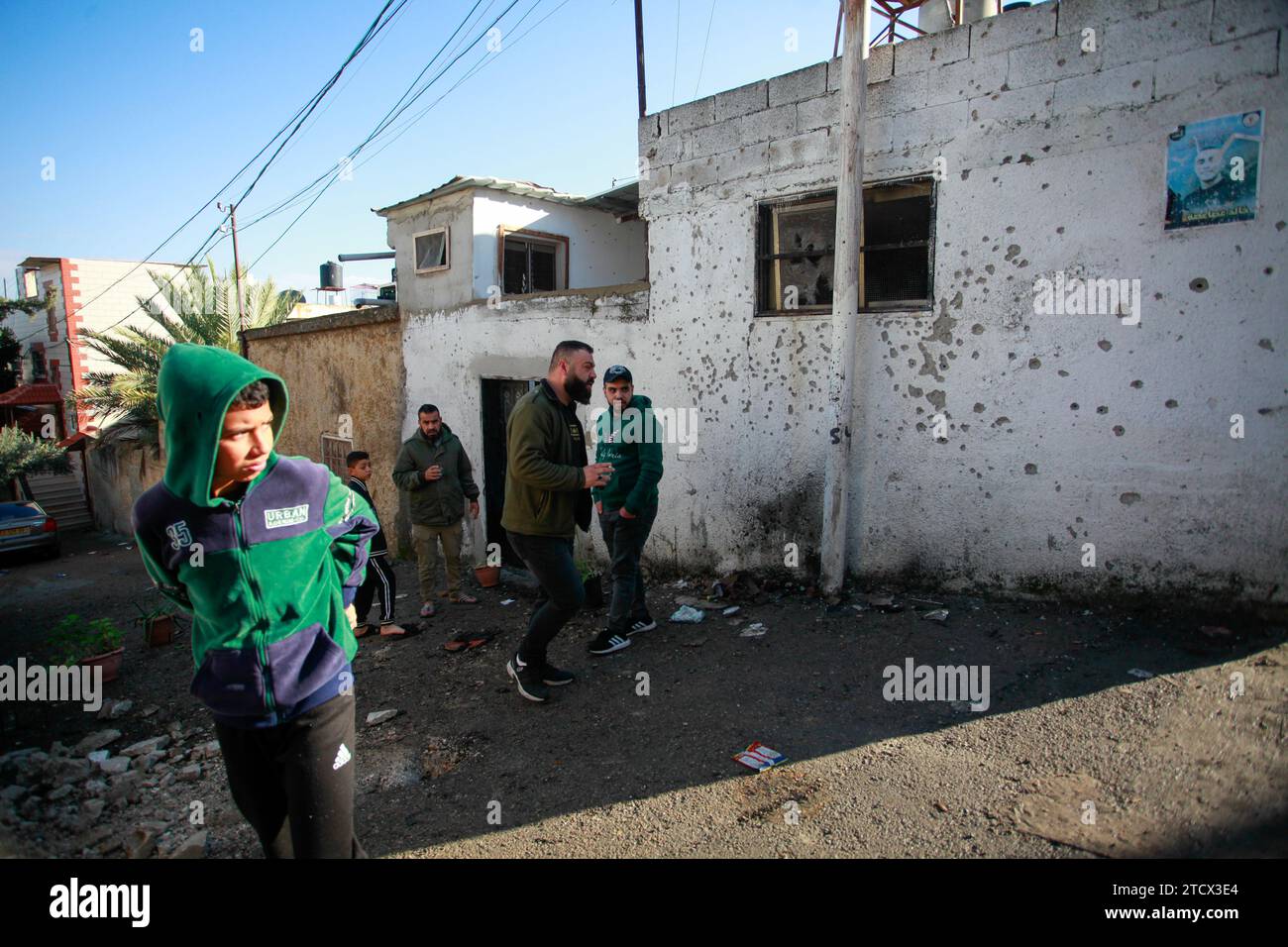 Jenin, Palestine. 14th Dec, 2023. Palestinians walk past a damaged ...