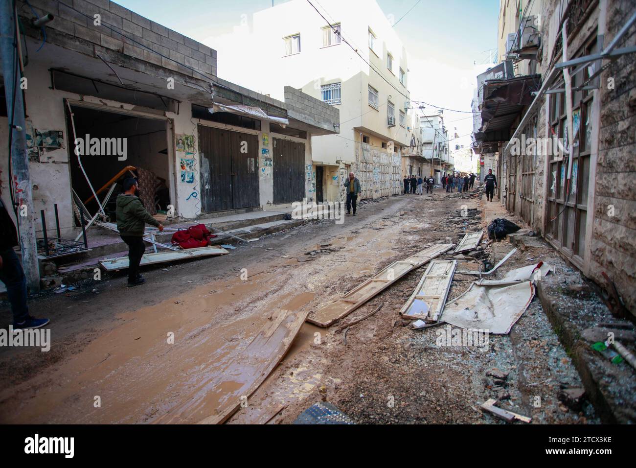 Jenin, Palestine. 14th Dec, 2023. Palestinians walk past damaged houses ...