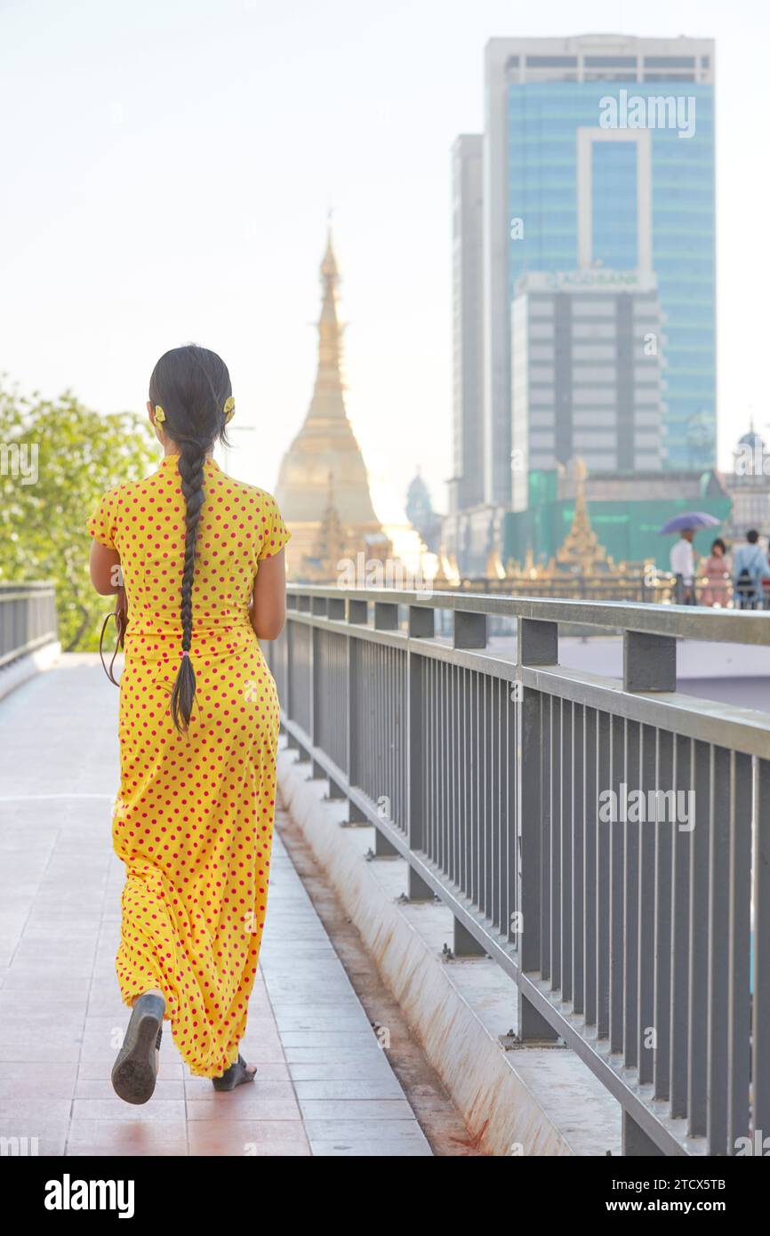 A girl with a traditional yellow dress in front of the Sule Pagoda in ...