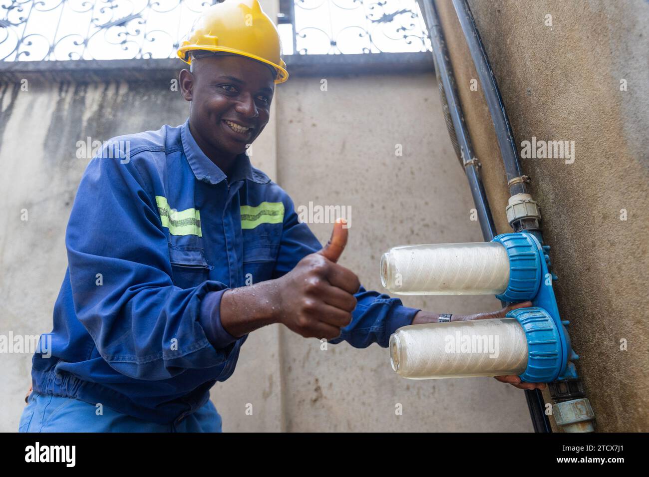 Thumbs up of a smiling African plumber, proud to have changed the water ...