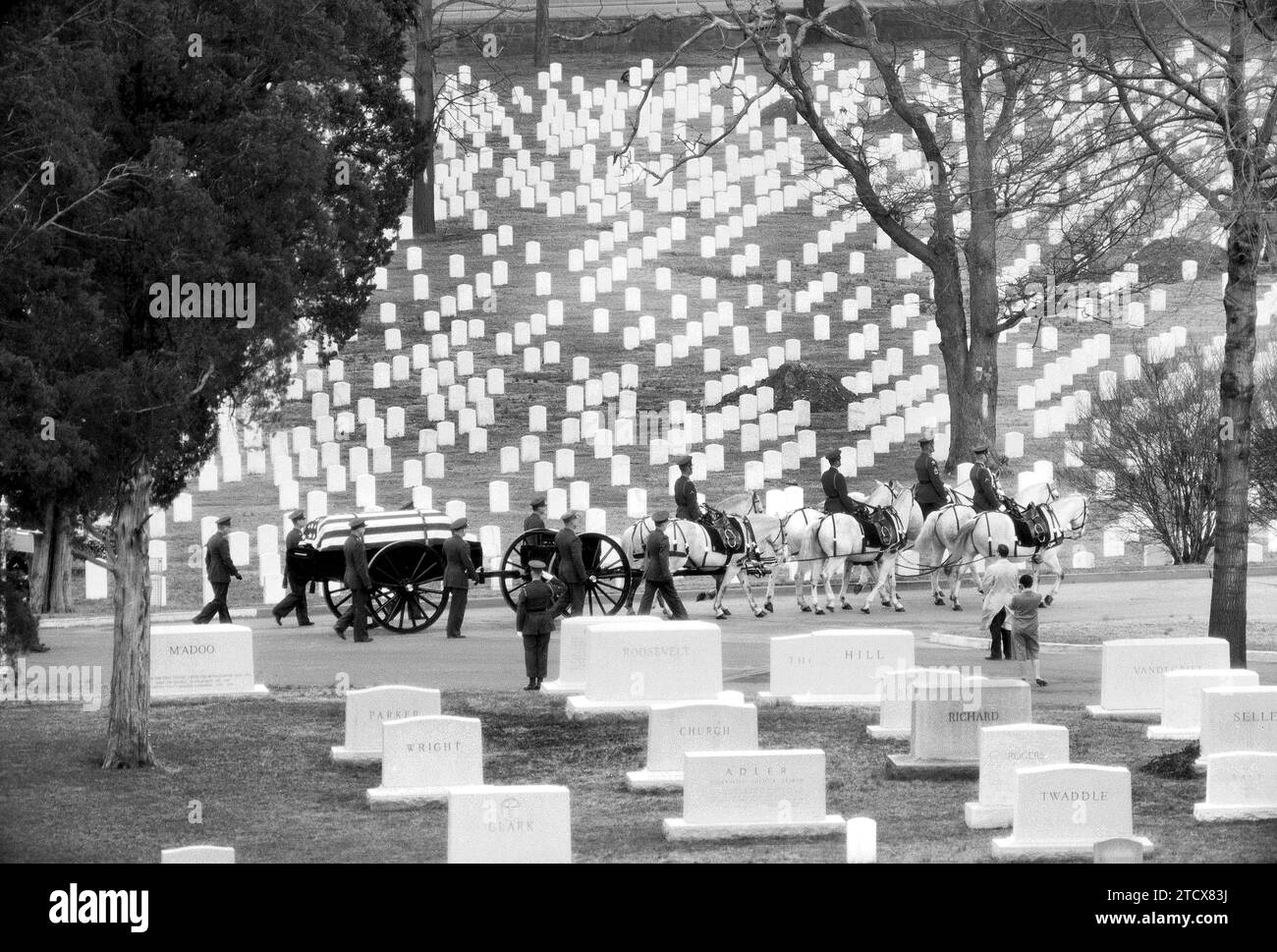 Flag-draped casket carried by horse-drawn caisson during a funeral, Arlington National Cemetery ...