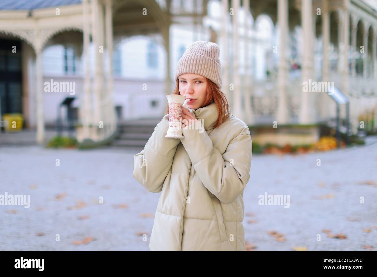 Young girl drinking from cup with therapeutic mineral water at a ...