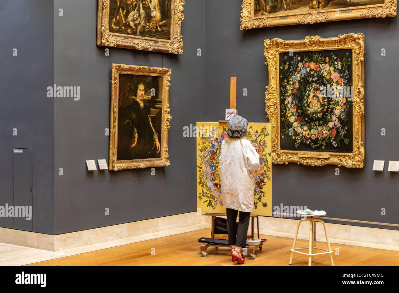 A female artist copying a painting in a gallery inside The Louvre ...
