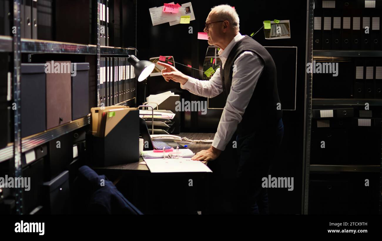 Private detective conducts investigation in incident room, looking at ...