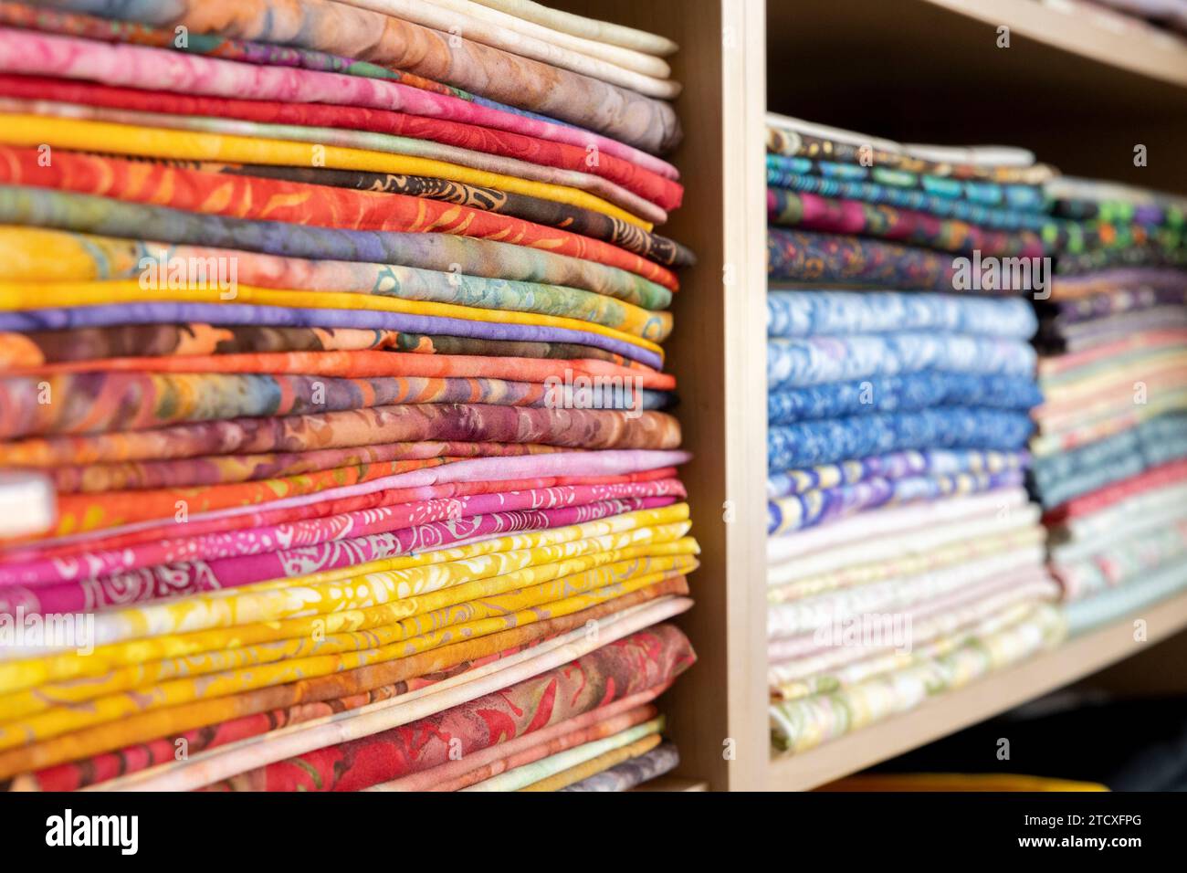 Stacks of colorful folded fabric on wooden shelves Stock Photo - Alamy