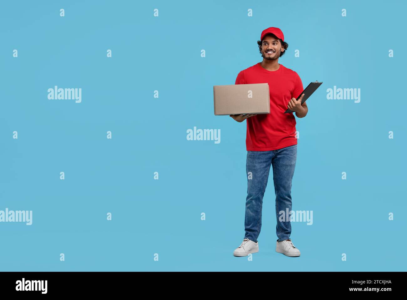 Happy courier with parcel and clipboard on light blue background, space ...