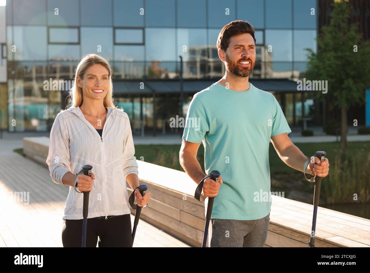 Happy couple practicing Nordic walking with poles outdoors Stock Photo ...