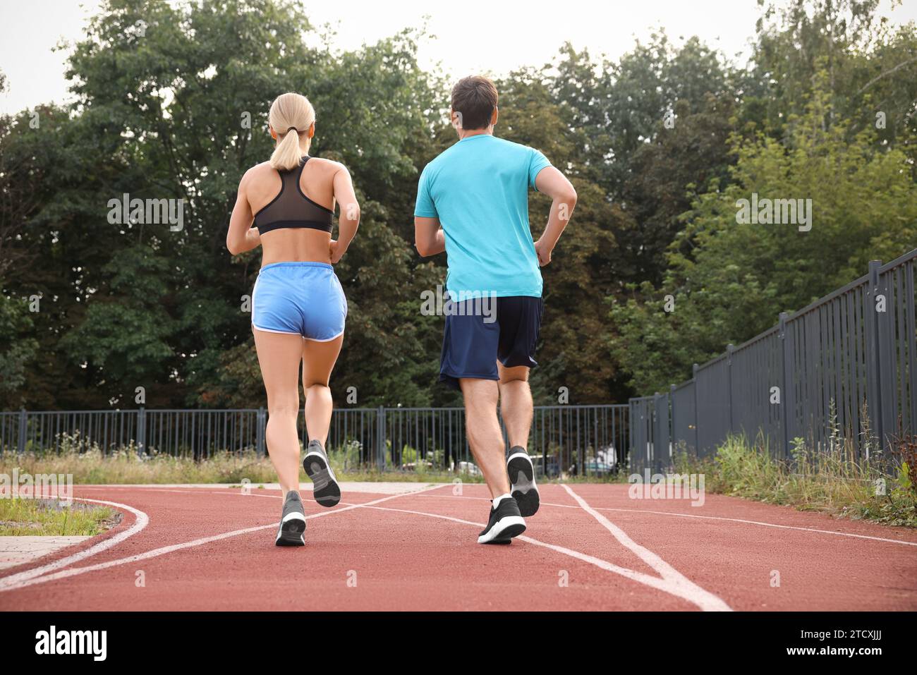 Healthy lifestyle. Sporty couple running at stadium, back view Stock ...