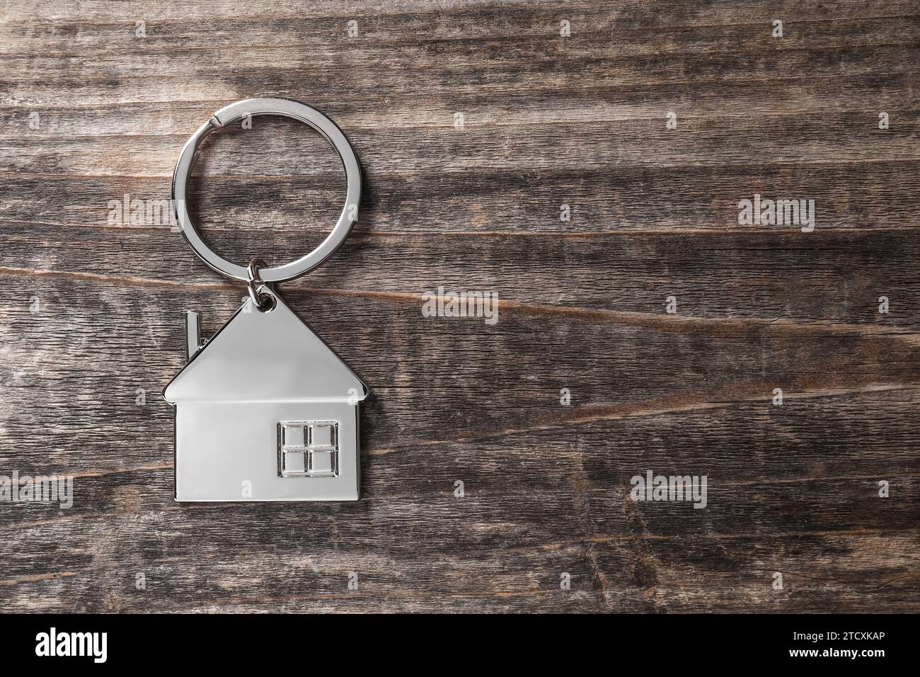 Metal keychain in shape of house on rustic wooden table, top view ...